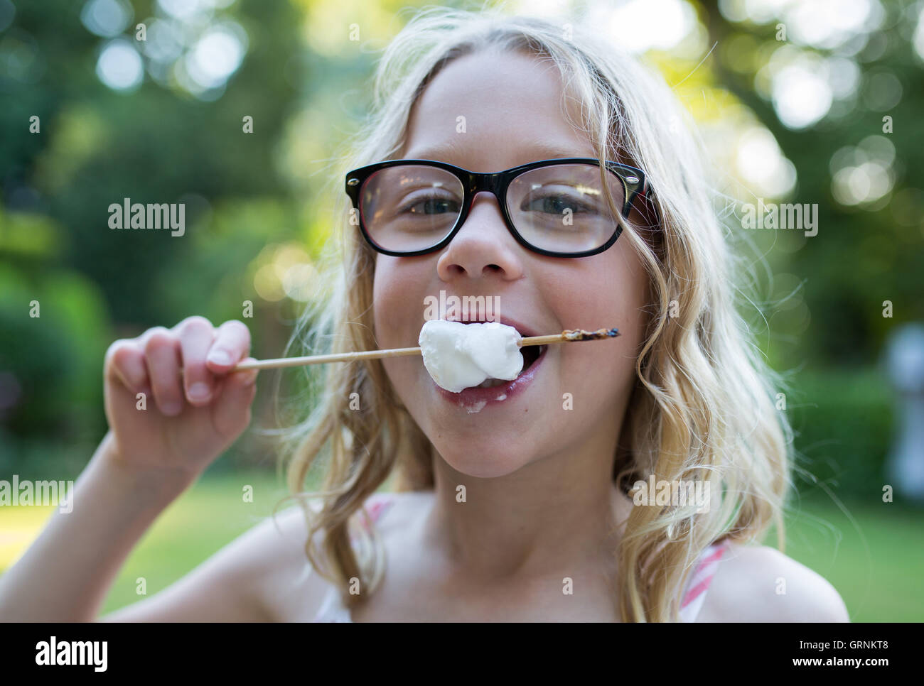 Girl eating marshmallow off a stick Stock Photo - Alamy