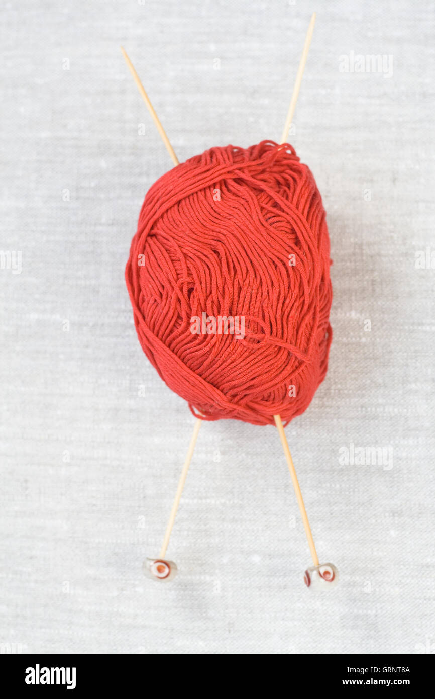 The big red skein of yarn for knitting, wooden needles on a light ...