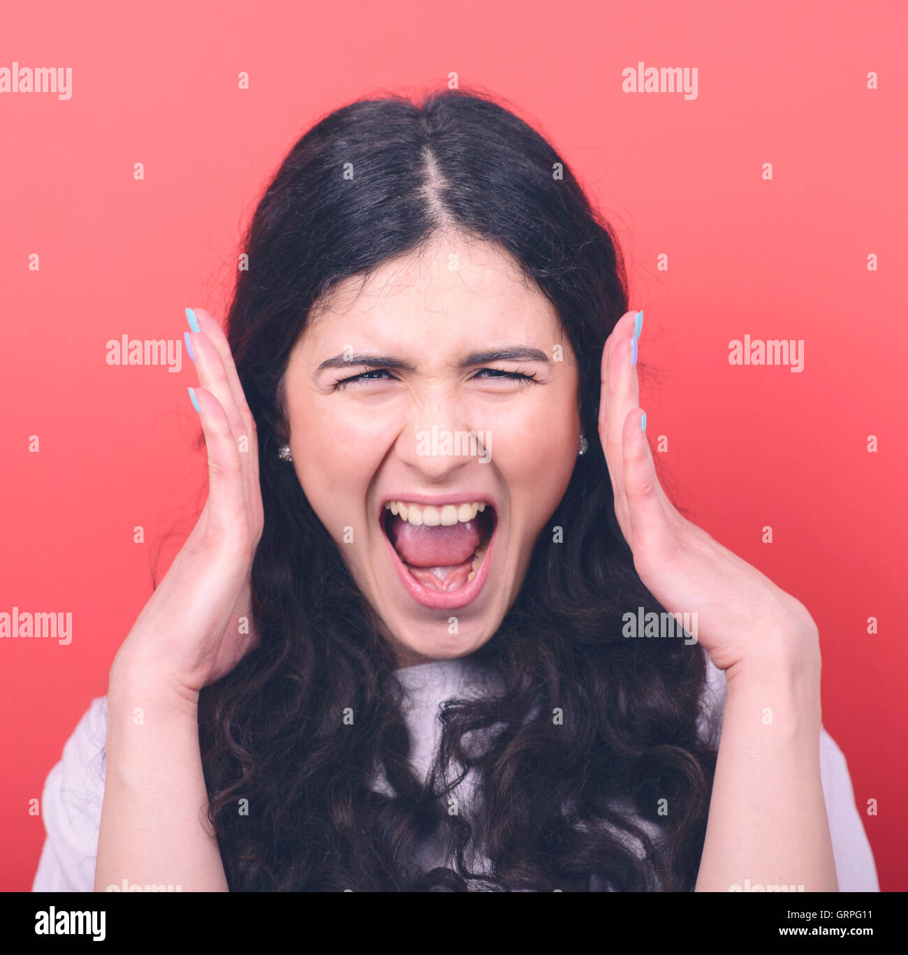 Portrait of angry girl screaming against red background Stock Photo - Alamy