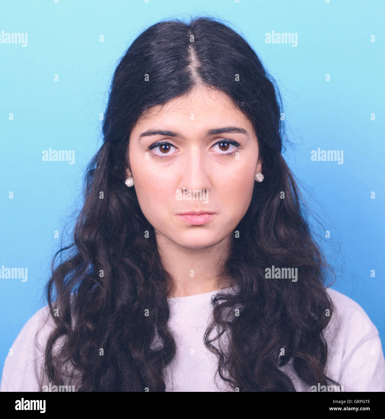 Portrait of sad girl against blue background Stock Photo - Alamy
