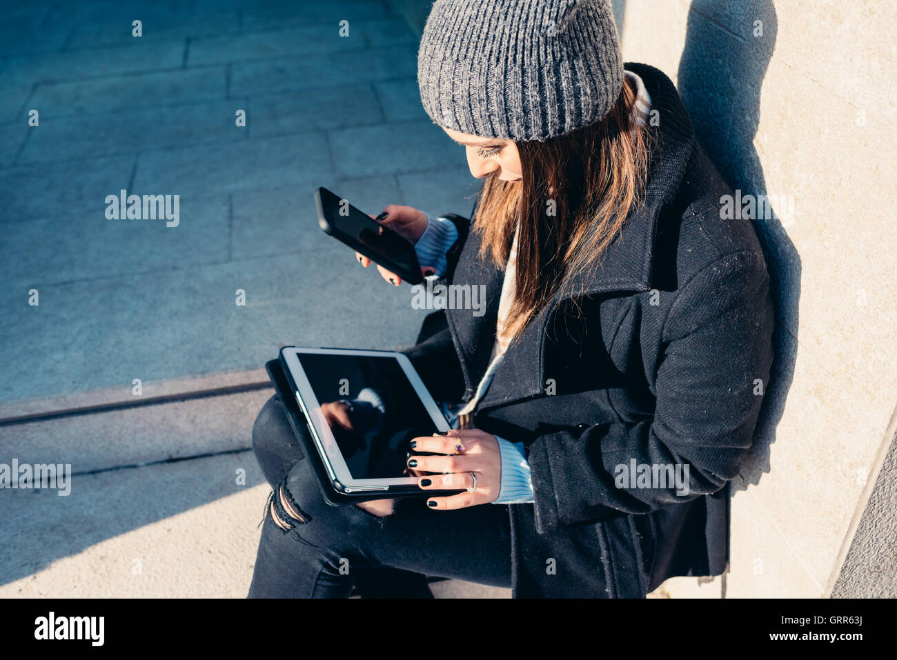 young woman tapping the screen of a tablet leaning on her knee and ...