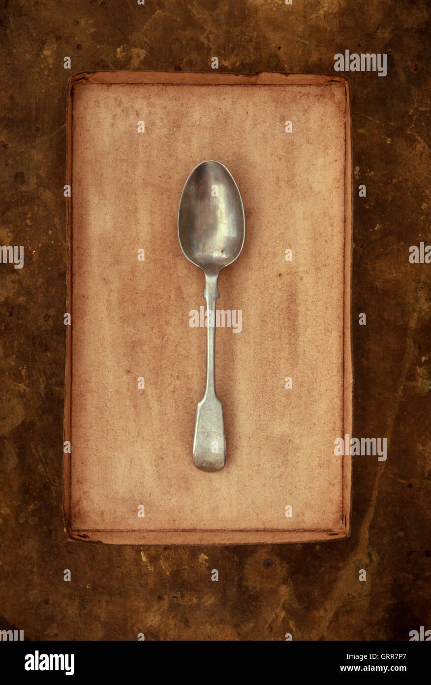 Slightly tarnished teaspoon lying in stained cardboard box on highly ...