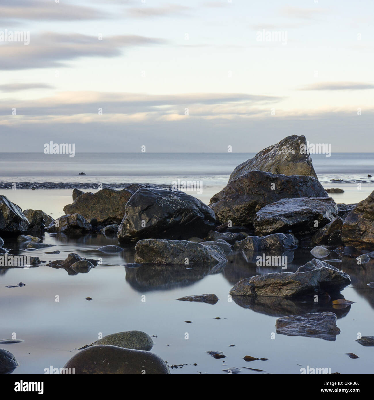 Rocks on the beach breakup the horizon line Stock Photo - Alamy