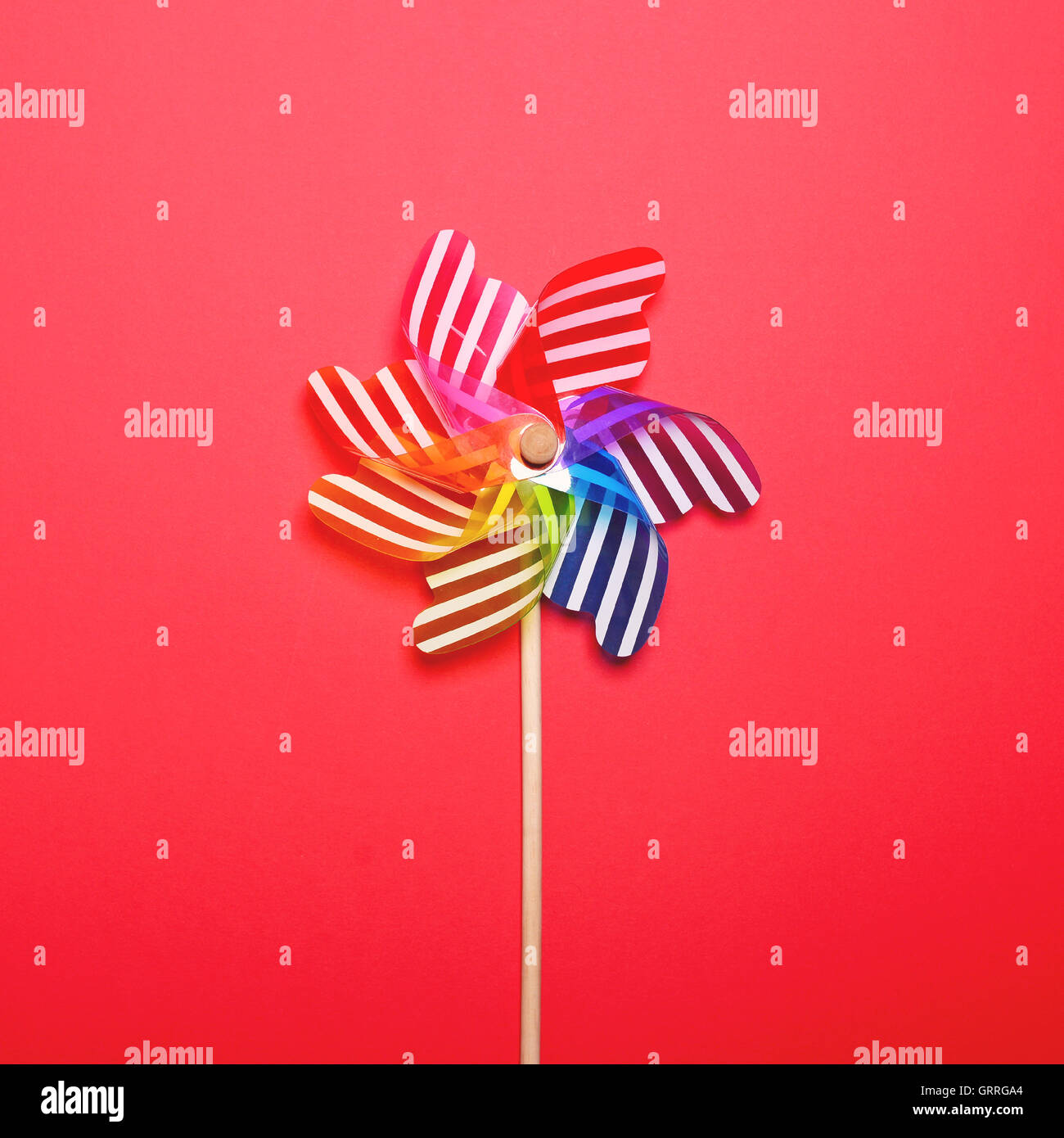 Multicolored pinwheel against red background - Minimal flat lay design ...