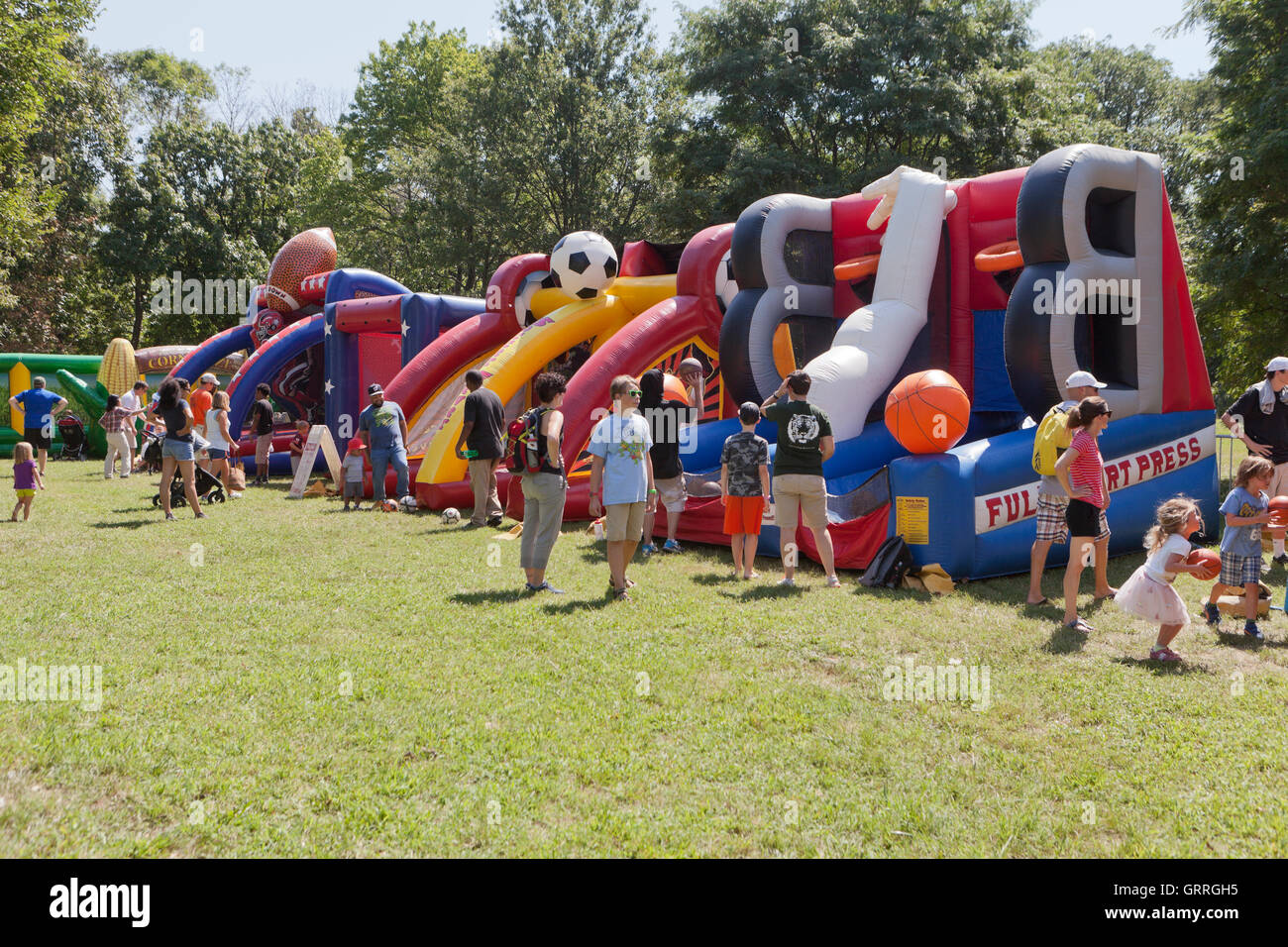 Children and parents playing at inflatable games at park - USA Stock ...