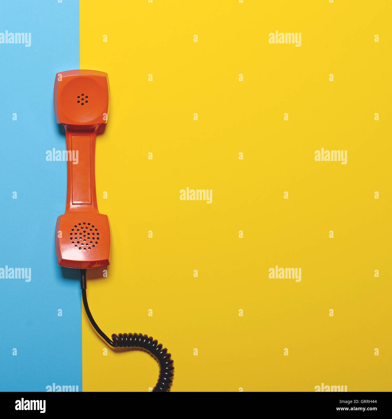 Retro orange telephone tube on striped blue and yellow background ...
