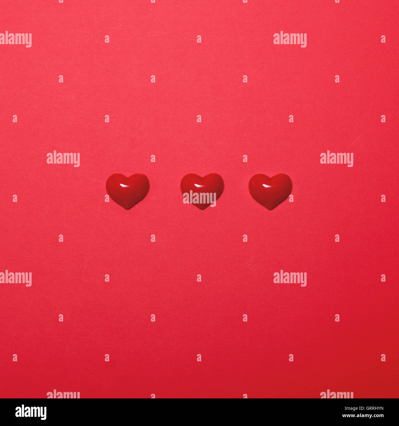 Three small hearts on red background - Minimal design Stock Photo - Alamy