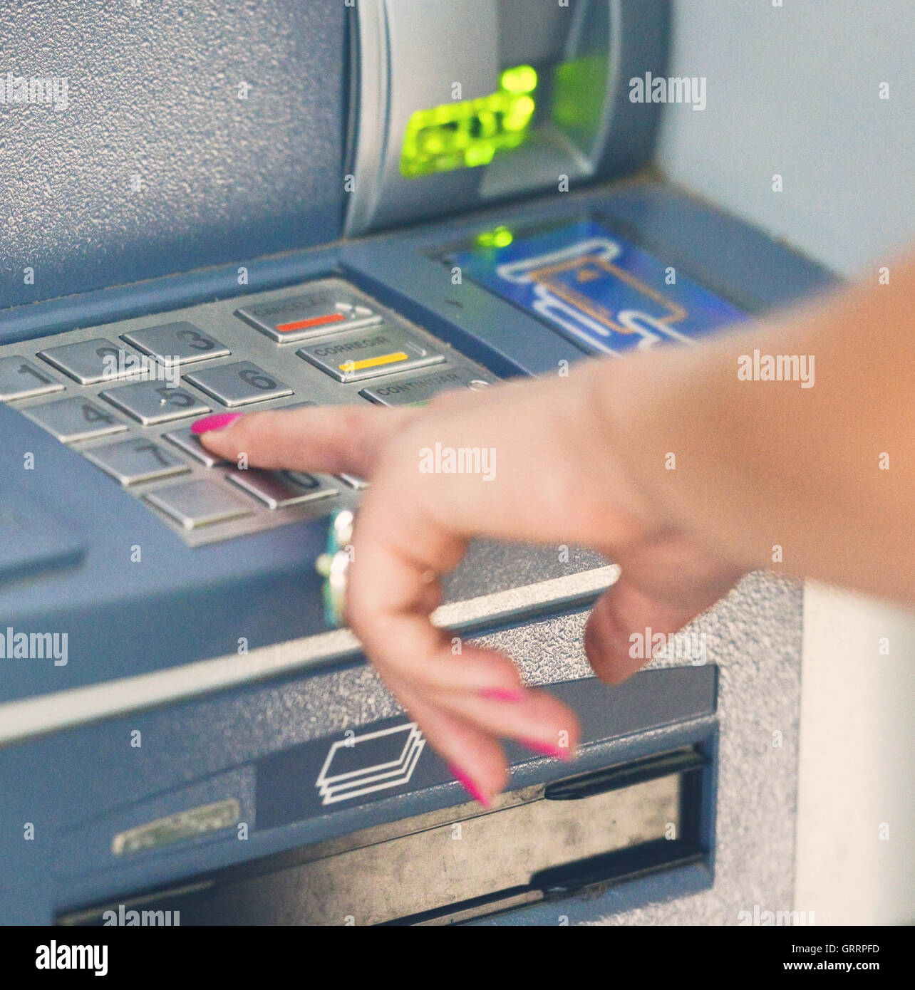 Close-up of hand entering PIN/pass code on ATM/bank machine keypad ...