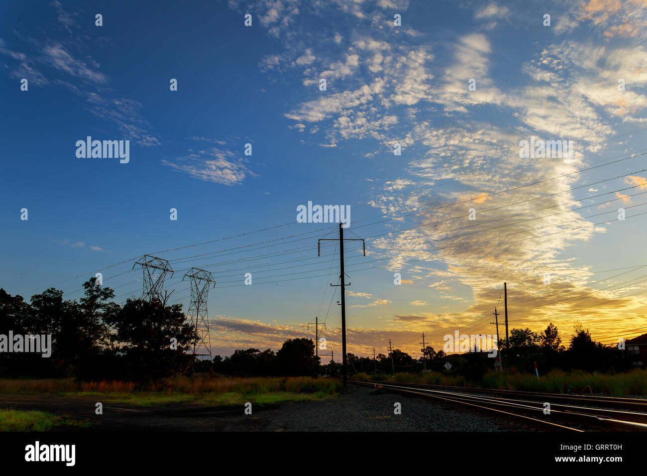 Cargo train platform at sunset. High voltage power pylons in sunset ...