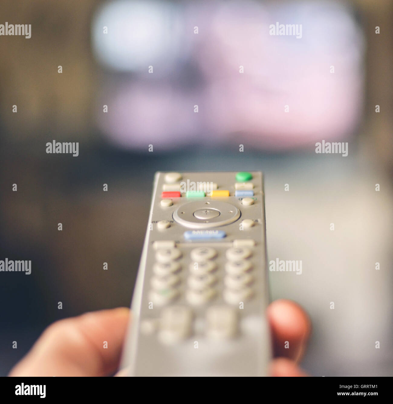 Hand holding remote controller with tv in the background Stock Photo ...