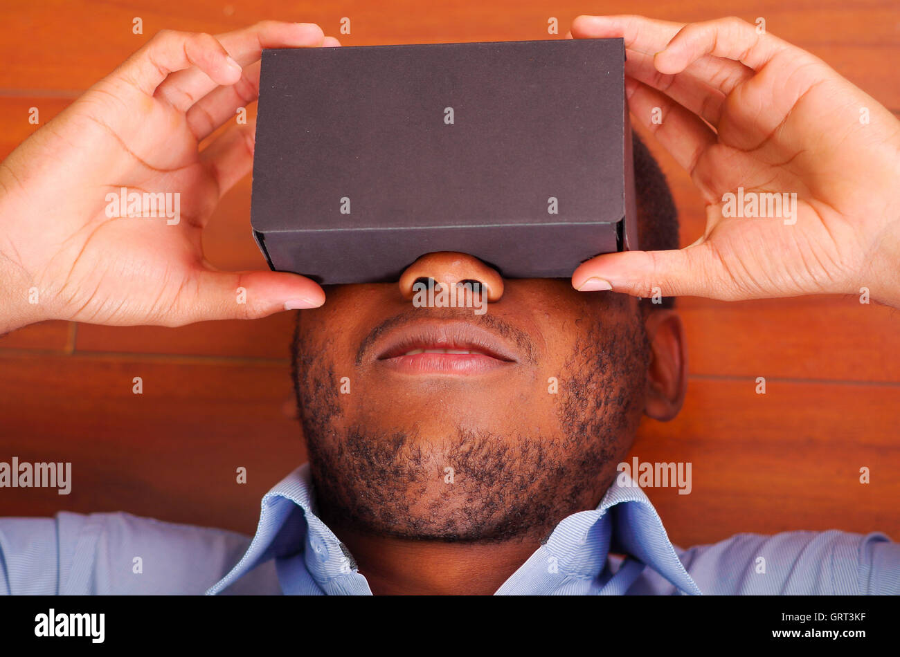 Headshot man lying down on wooden floor playing with virtual reality ...