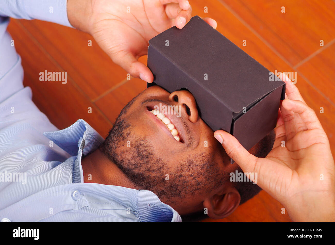 Headshot man lying down on wooden floor playing with virtual reality ...