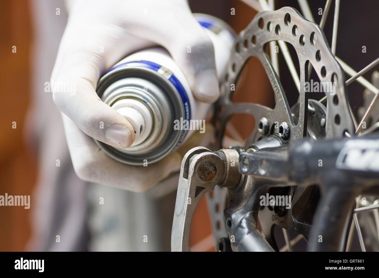 Closeup hand wearing white glove using grease spray on cogwheel parts ...