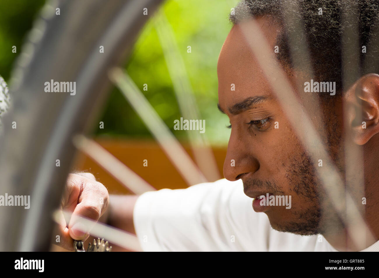 Man wearing white shirt concentrated working on repairing bicycle ...