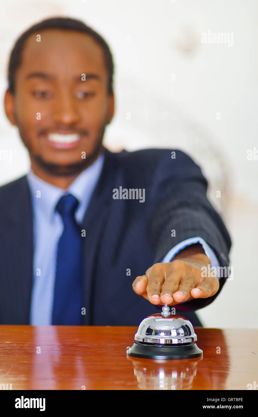 Man wearing elegant blue suit pressing desk bell at hotel reception ...