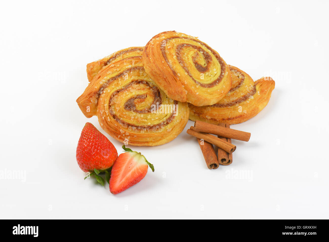 sweet cinnamon rolls, cinnamon sticks and strawberries on white ...
