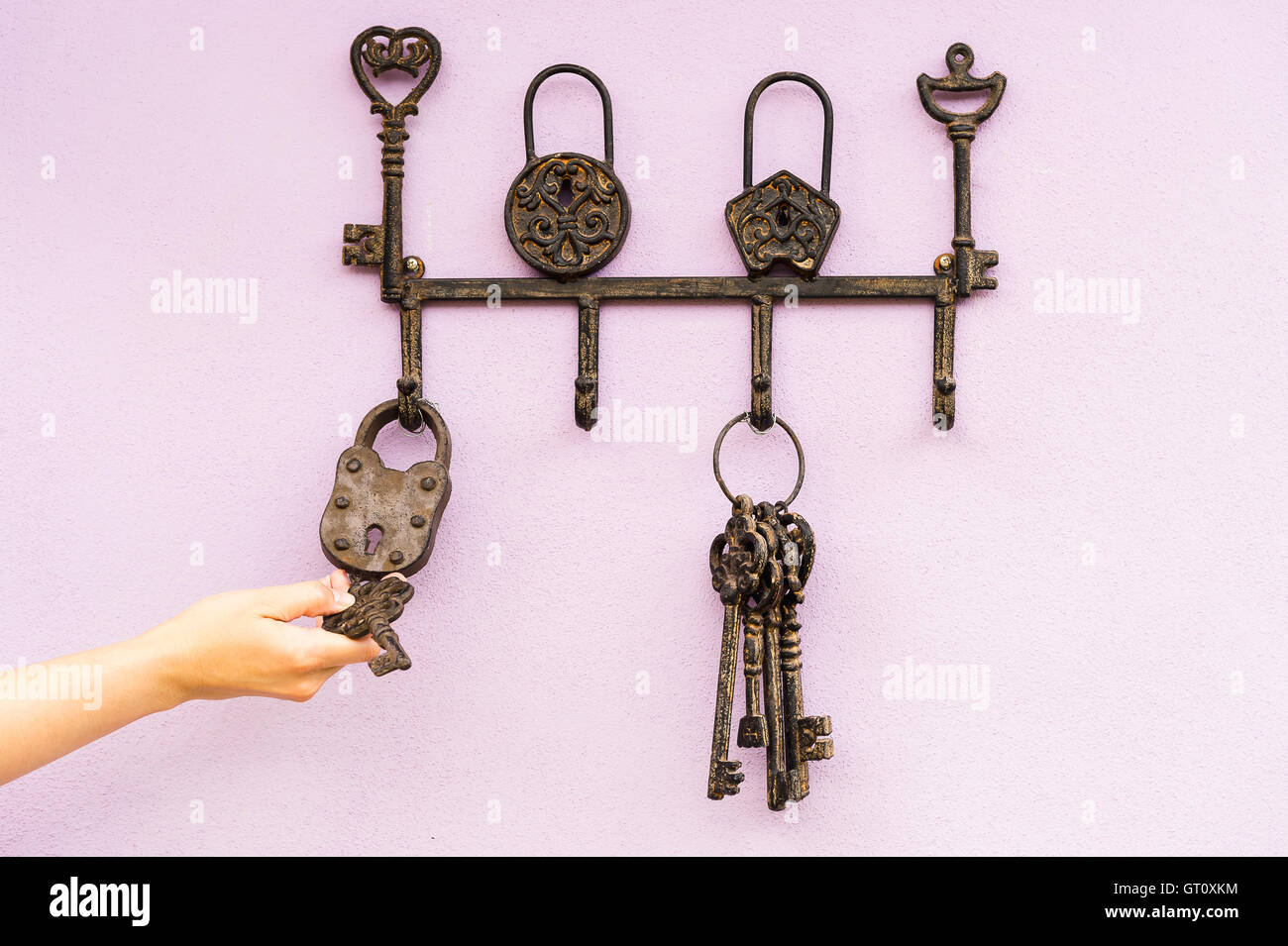 hand with brass antique skeleton keys hanging on pink wall Stock Photo ...