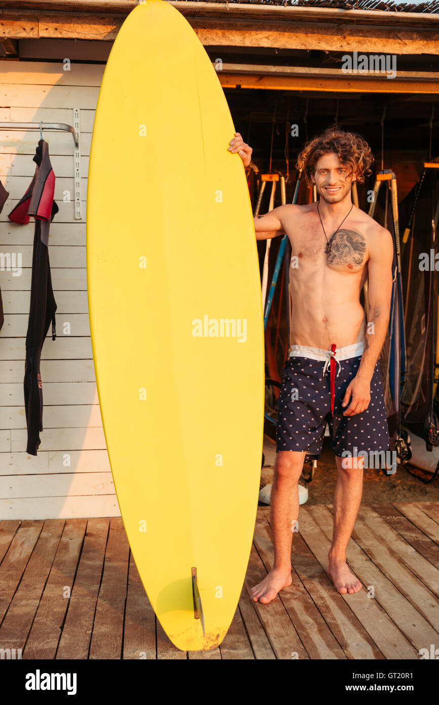 Full length portrait of professional young surfer getting board ready ...