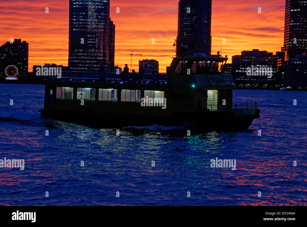 A ferry boat crossing the Hudson River in New York harbor at sunset ...