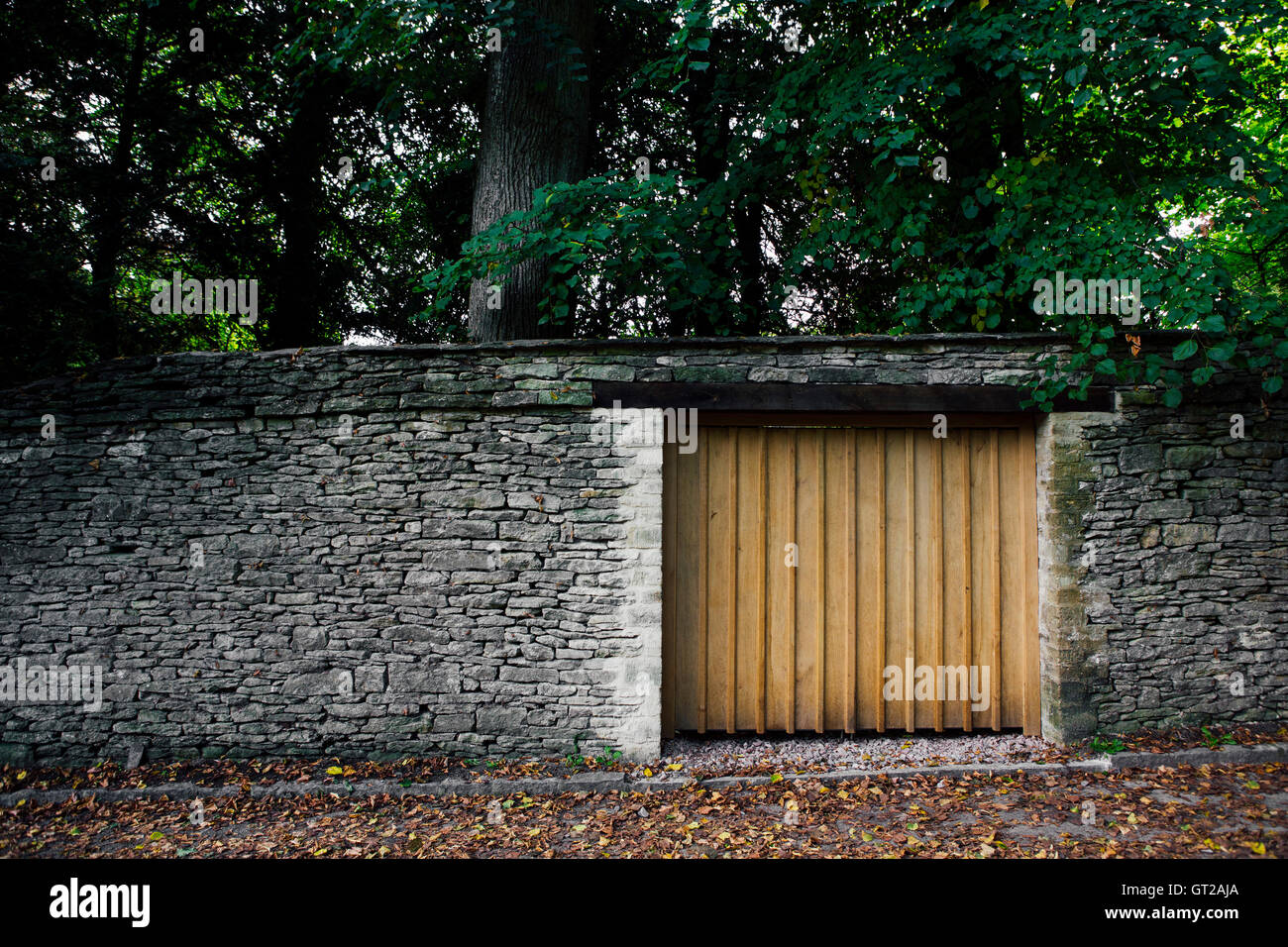 Simple wooden gate in a stone wall like a garage door at the entrance ...