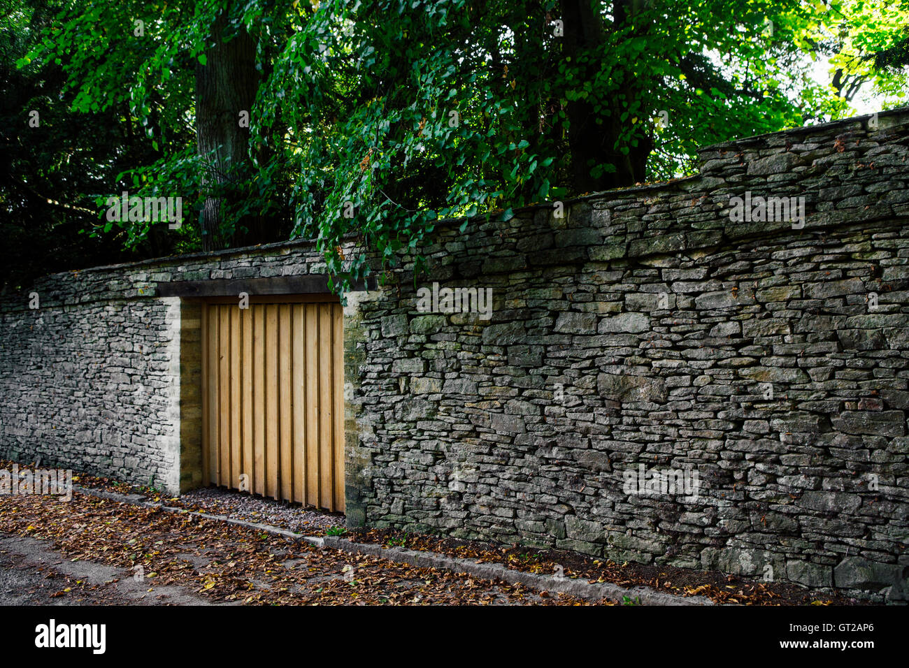 Simple wooden gate in a stone wall like a garage door at the entrance to a private porperty in ...