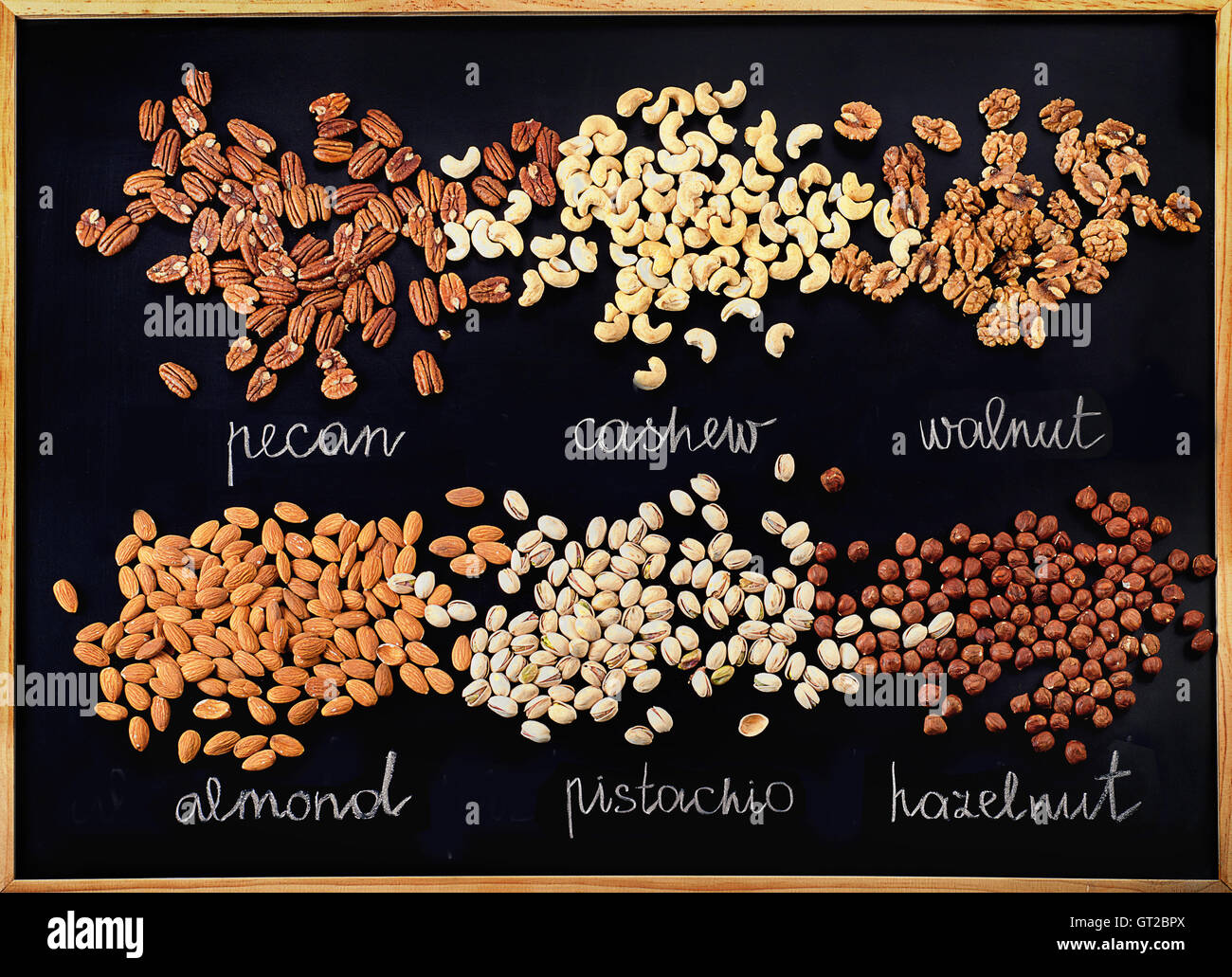 Different types of nuts on blackboard. Top view Stock Photo - Alamy