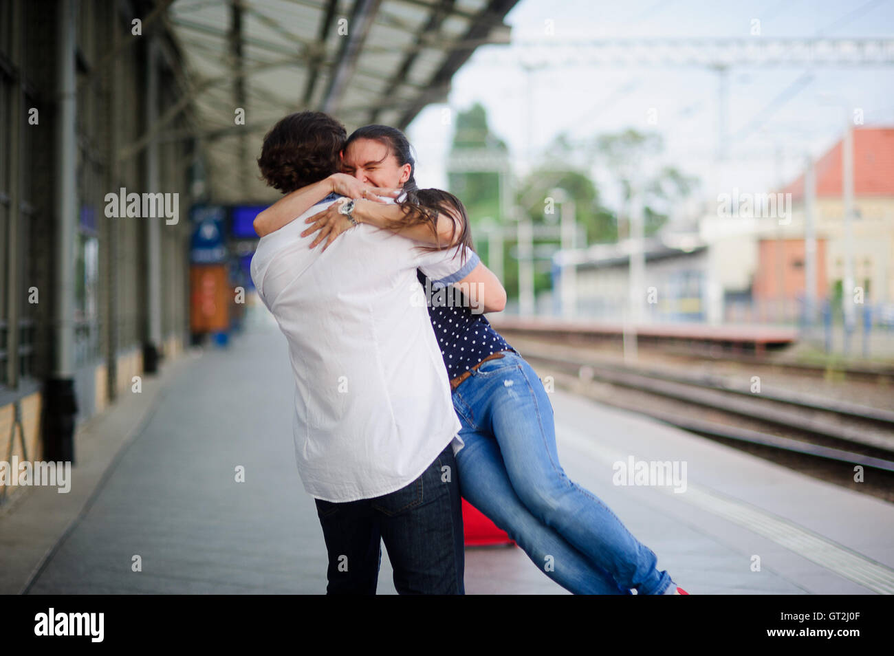 Joyful meeting at the railway station. The young man lifted the girl ...