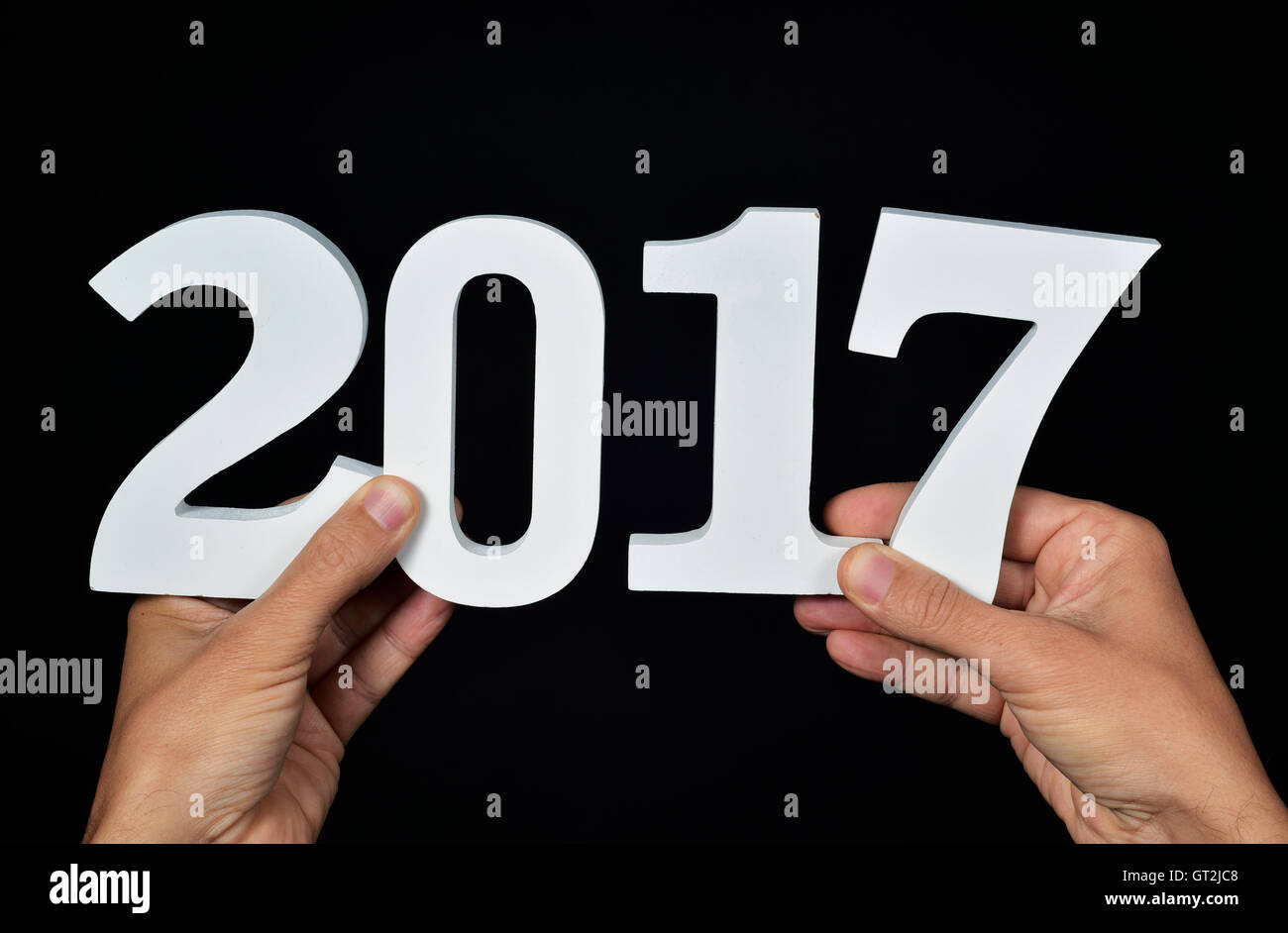 young man holding some white numbers forming the number 2017, as the ...