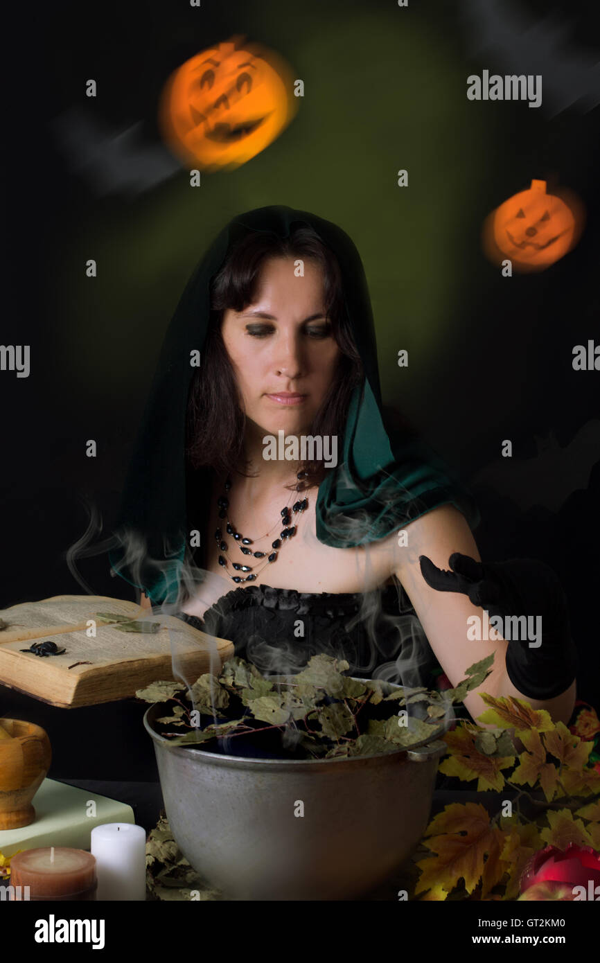 Witch making magic with book Stock Photo - Alamy
