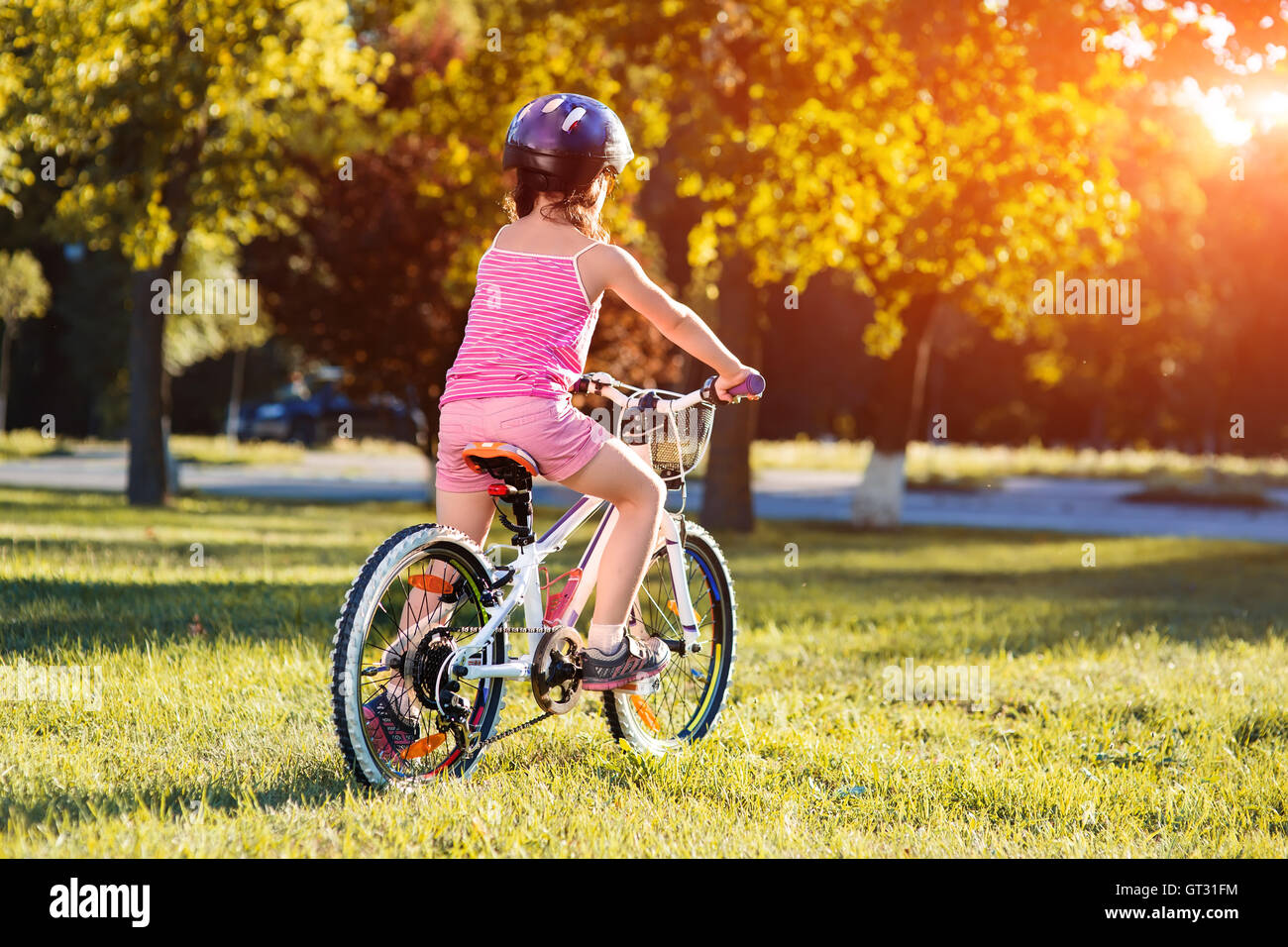 child girl riding bicycle on summer sunset in the park Stock Photo - Alamy