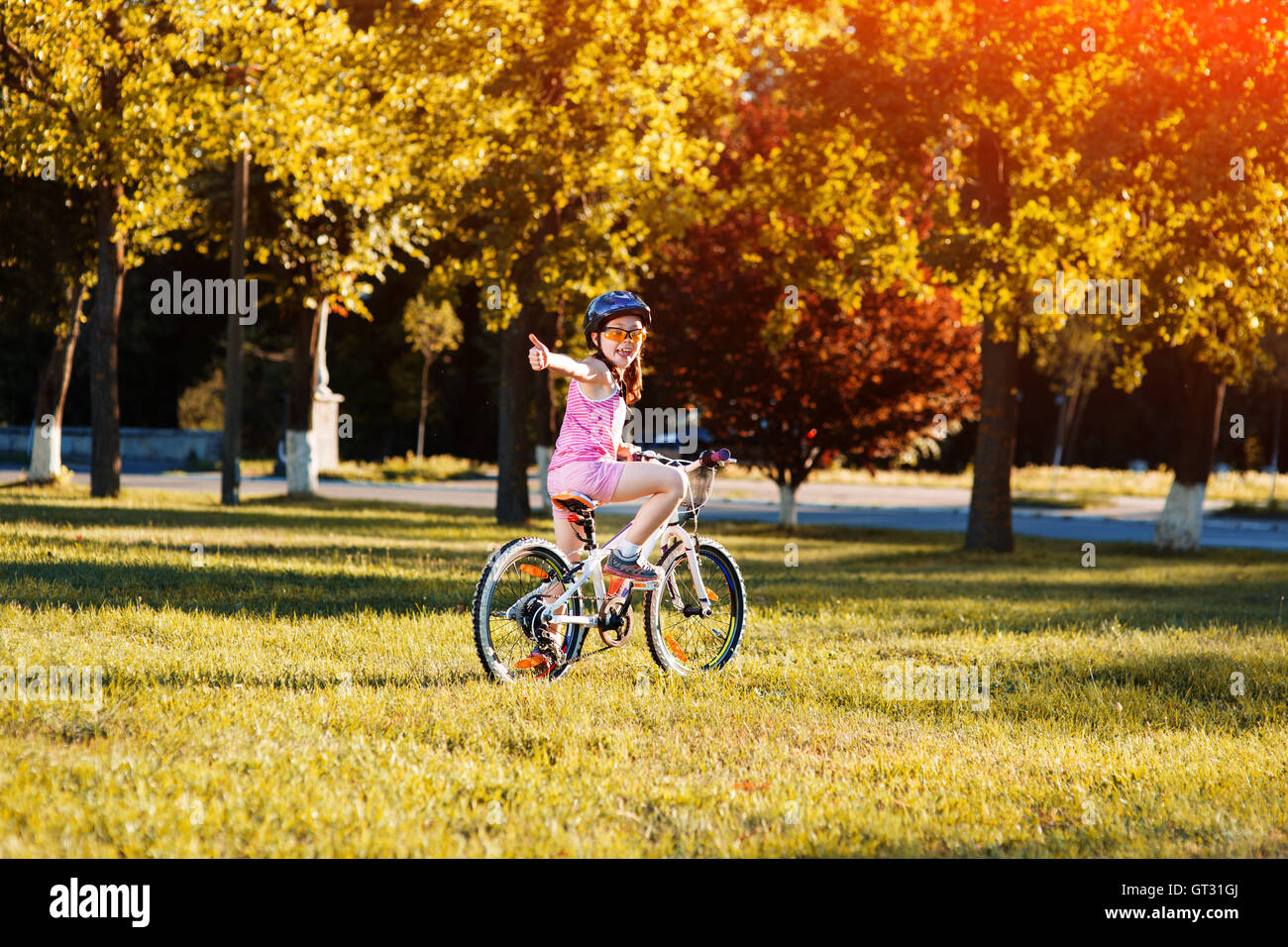 child girl riding bicycle on summer sunset in the park Stock Photo - Alamy