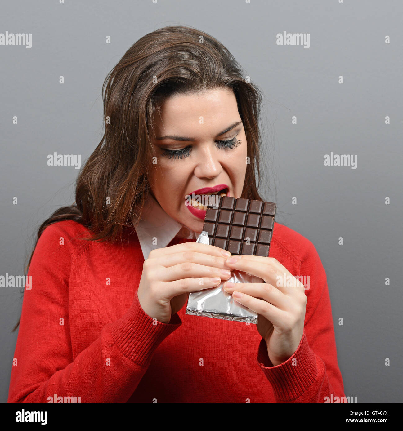 Beautiful woman eating chocolate against gray background Stock Photo ...