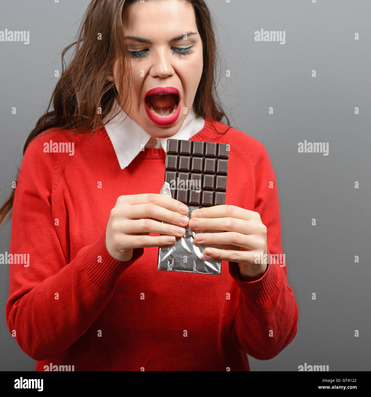Beautiful woman eating chocolate against gray background Stock Photo ...