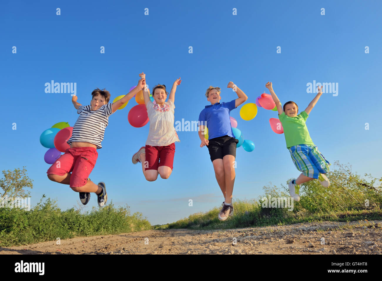 happy children jumping on field with balloons Stock Photo - Alamy