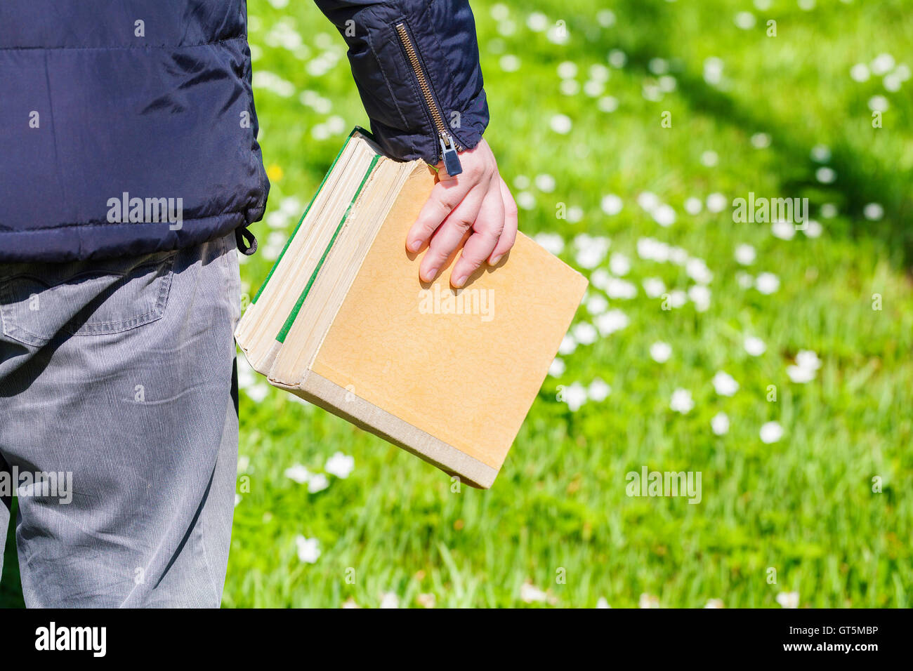 Man with books on green meadow Stock Photo - Alamy