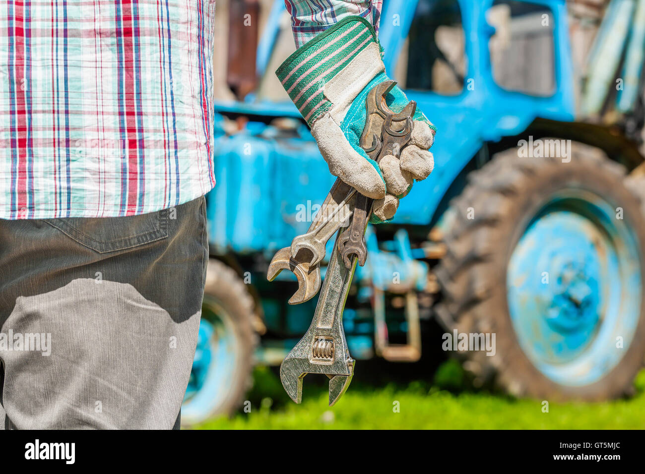 Worker with adjustable wrench near the tractor Stock Photo - Alamy