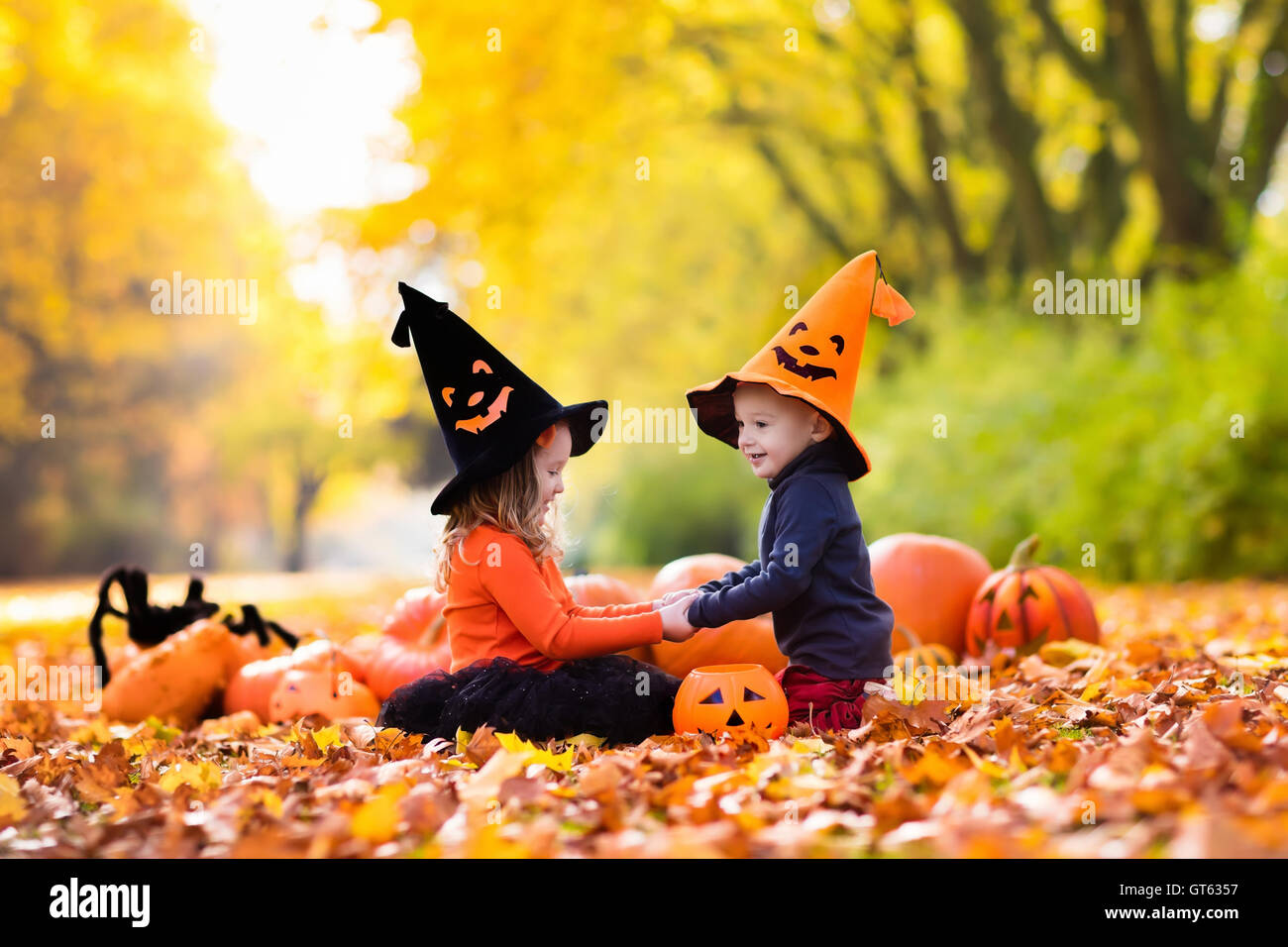 Children wearing black and orange witch costumes with hats playing with ...
