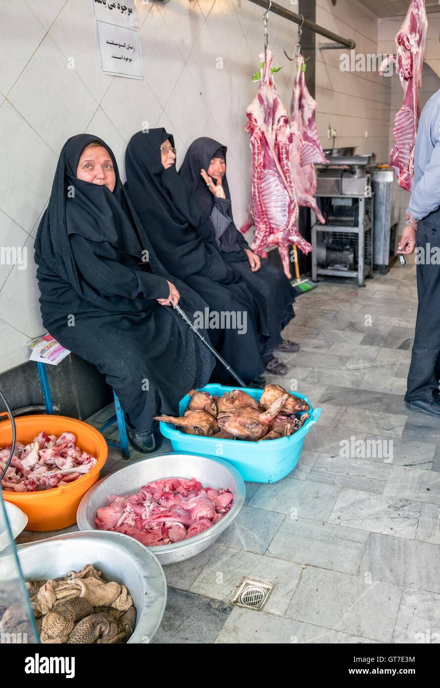 Women in chadors waiting in the butcher shop with tubs of goat heads ...