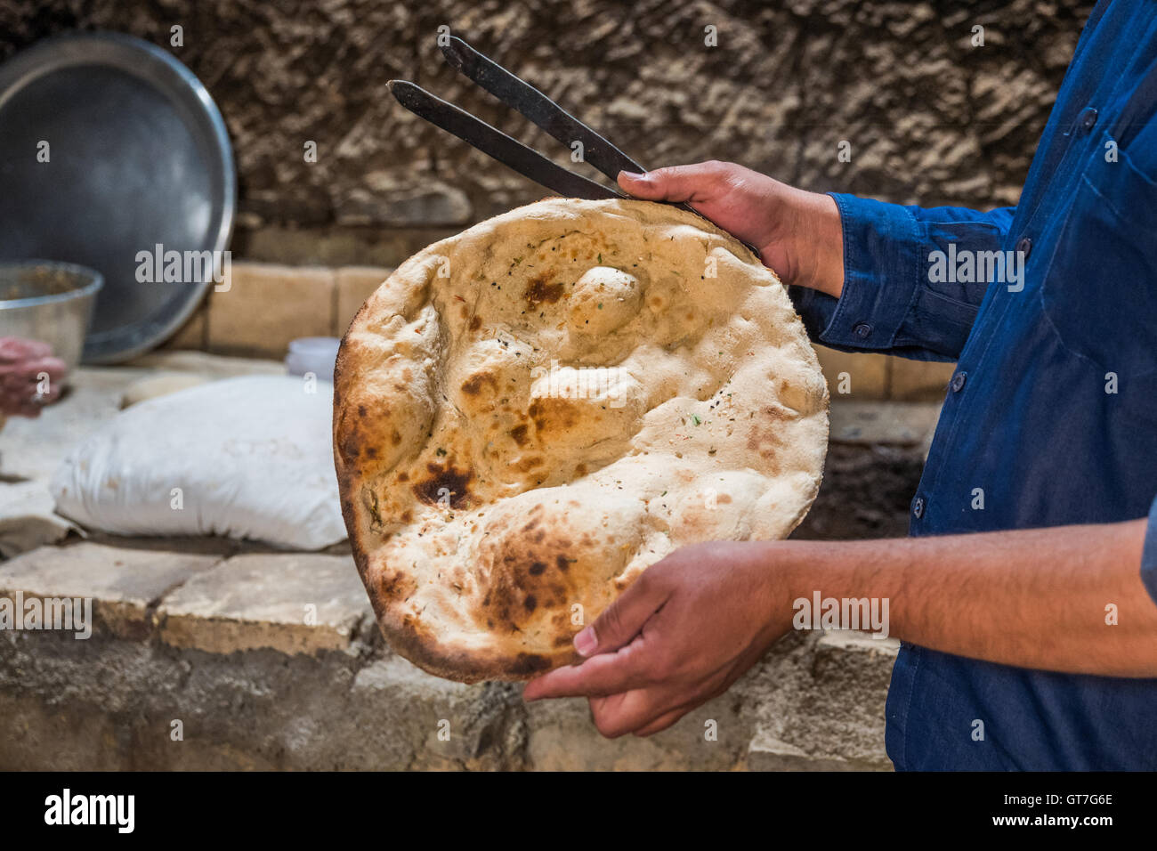 Taftoon bread baking in tandoori oven in traditional restaurant run by ...