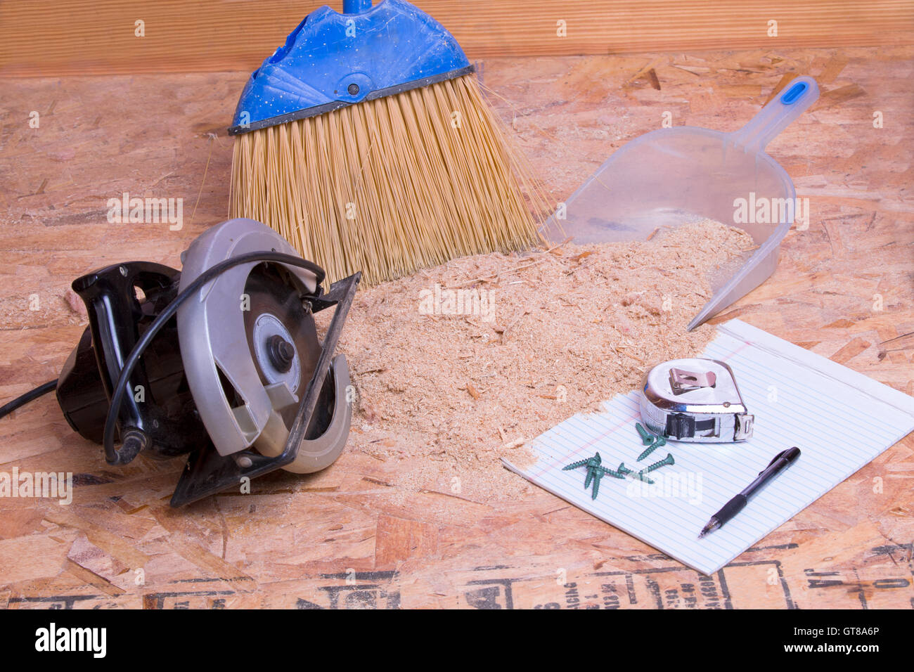 Handheld circular saw with sawdust, brush and pan lying on the floor ...