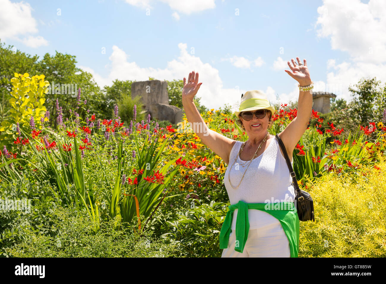 Trendy joyful Grandma outdoors in her garden laughing and waving her ...