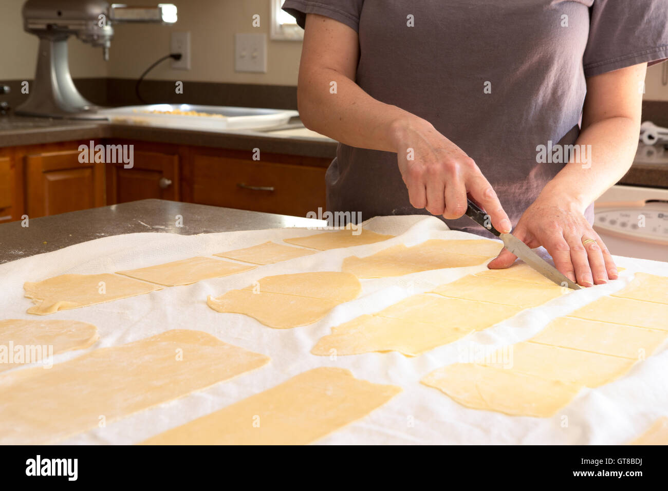 Chef trimming homemade speciality rolled pasta dough in a kitchen ...