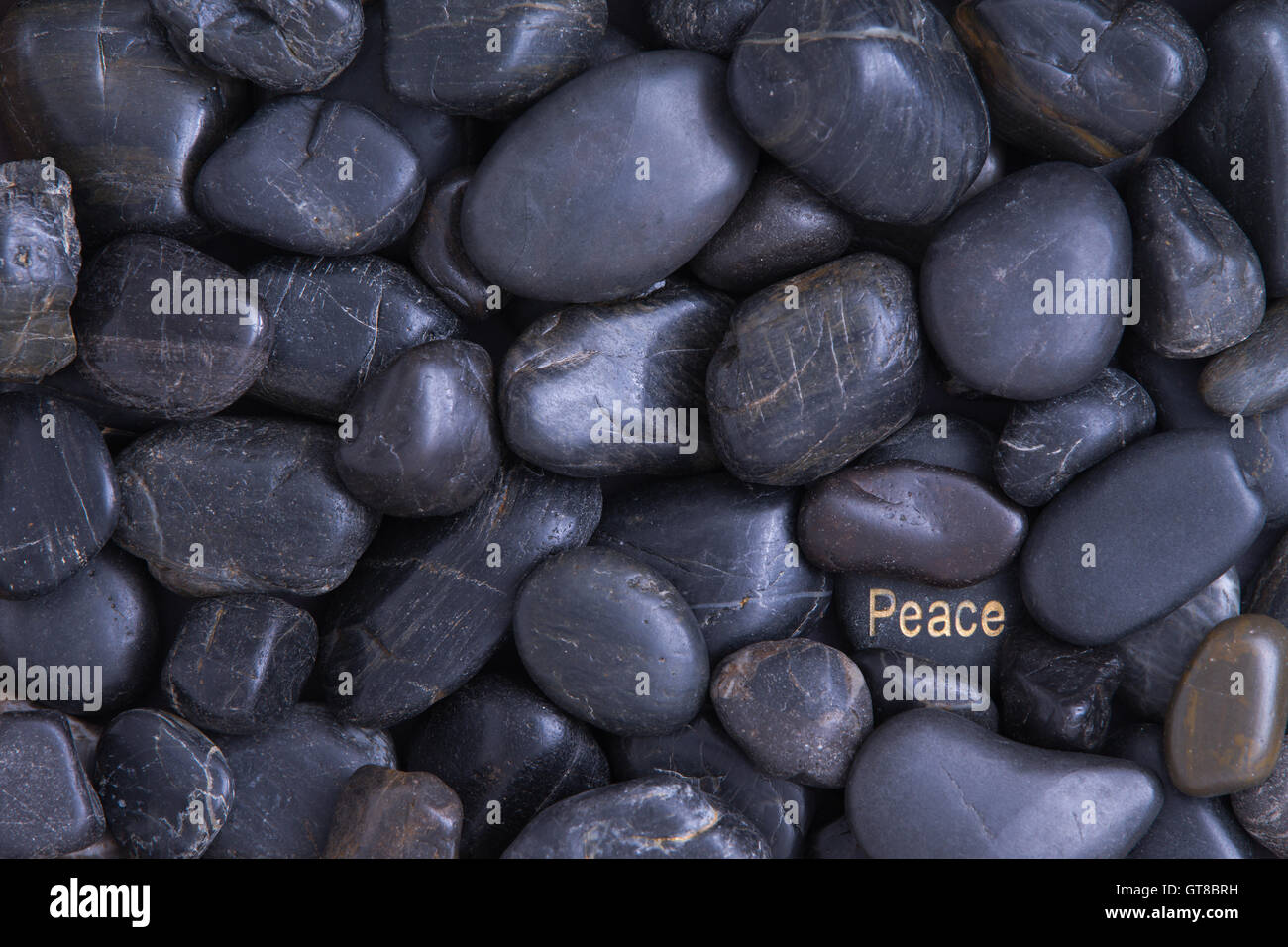 Smooth waterworn smooth black pebble full frame background with a Peace ...