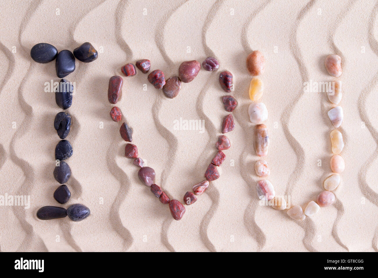 I Love You romantic message in colorful pebbles on golden beach sand ...