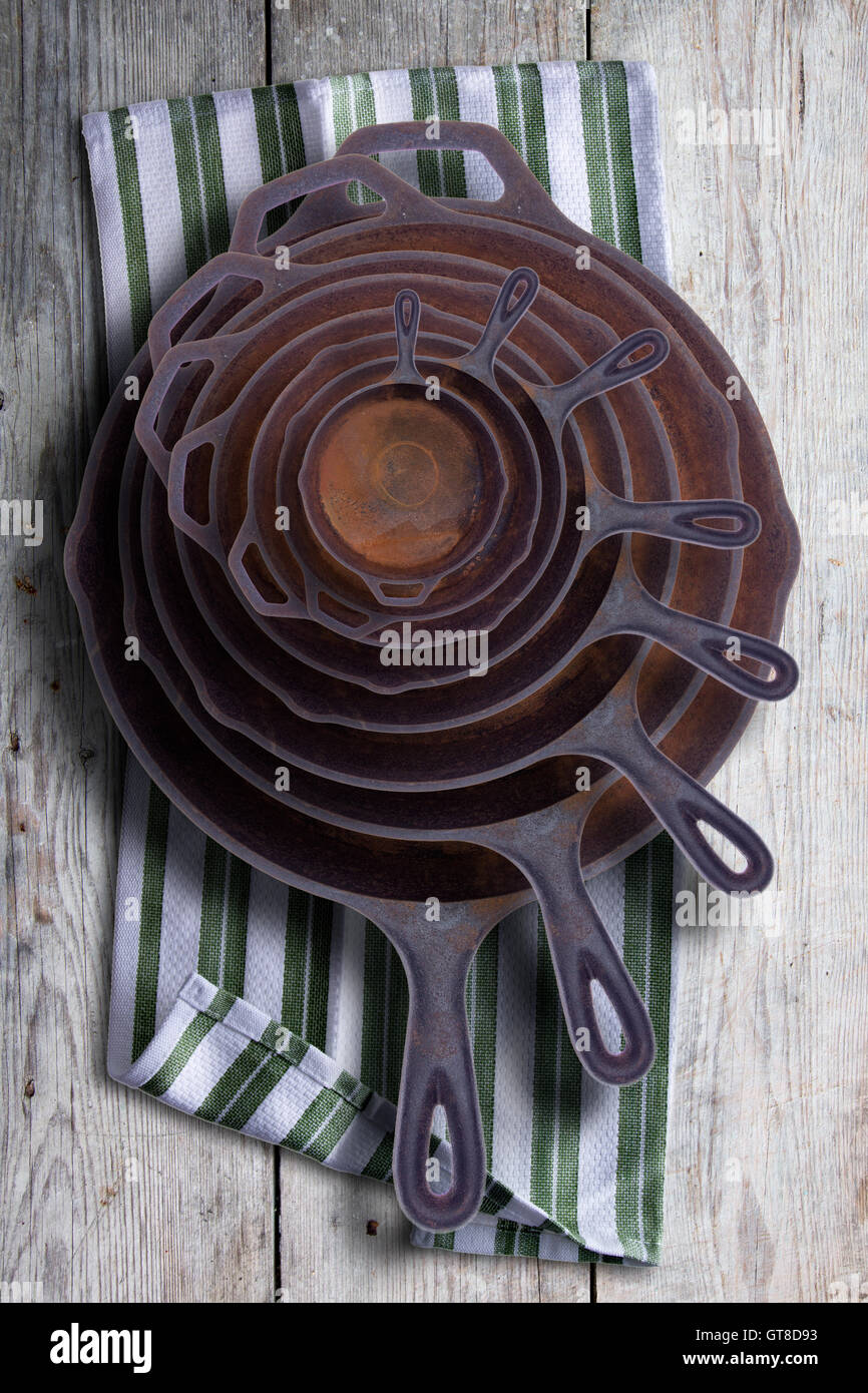 Collection of round rusty cast iron frying pans in diminishing sizes ...