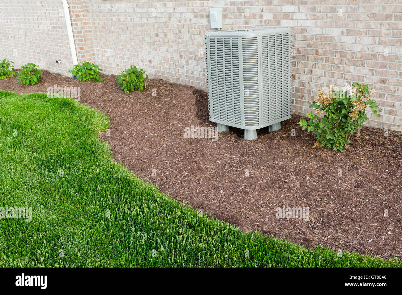 Air conditioner condenser unit standing outdoors in a garden in a neat ...