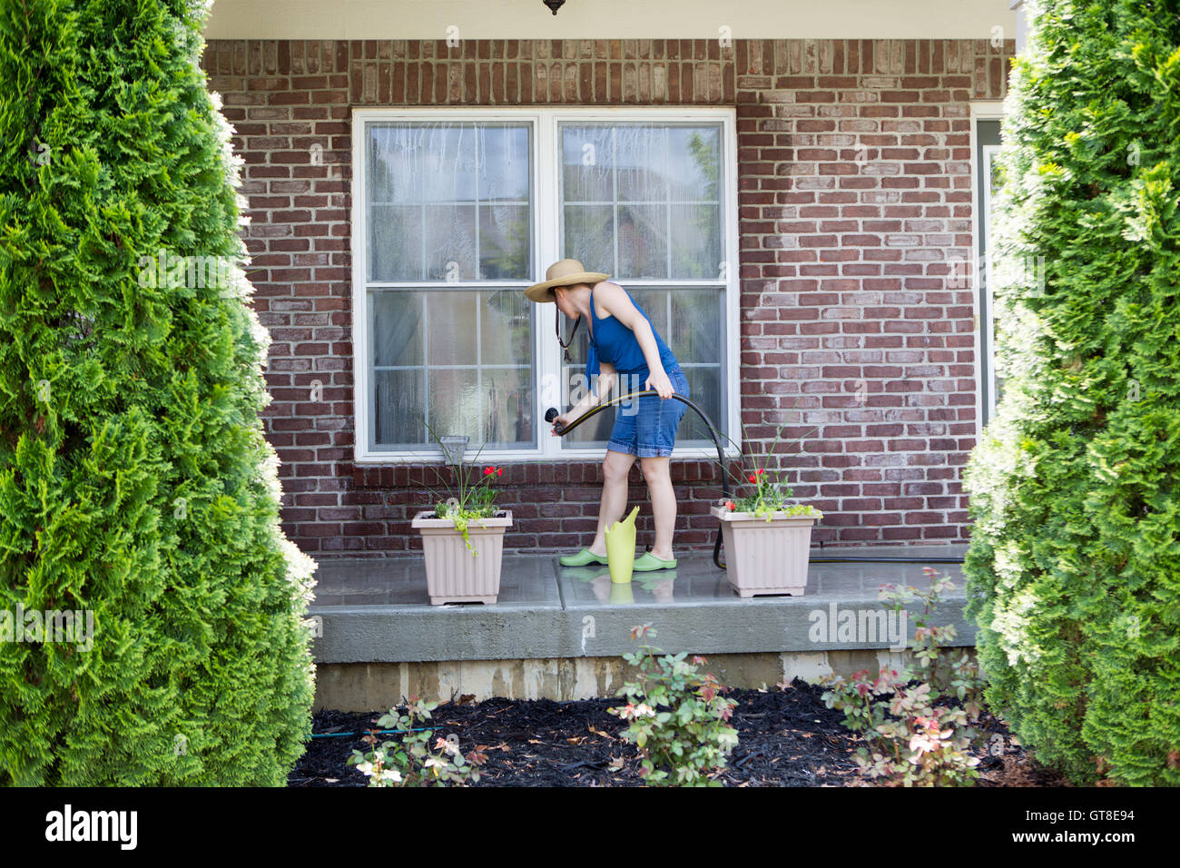 Woman washing the exterior windows of a house with an attachment on a ...