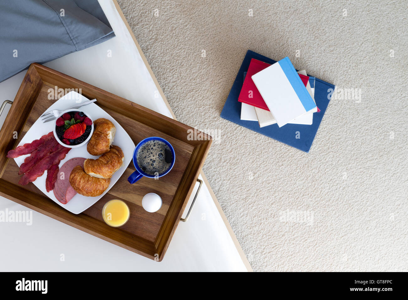 High Angle View of Stack of Books on Floor Beside Bed with Breakfast in ...