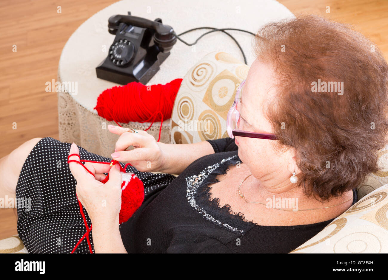 Grandma Sitting Knitting On A Couch In The Living Room Near The Old