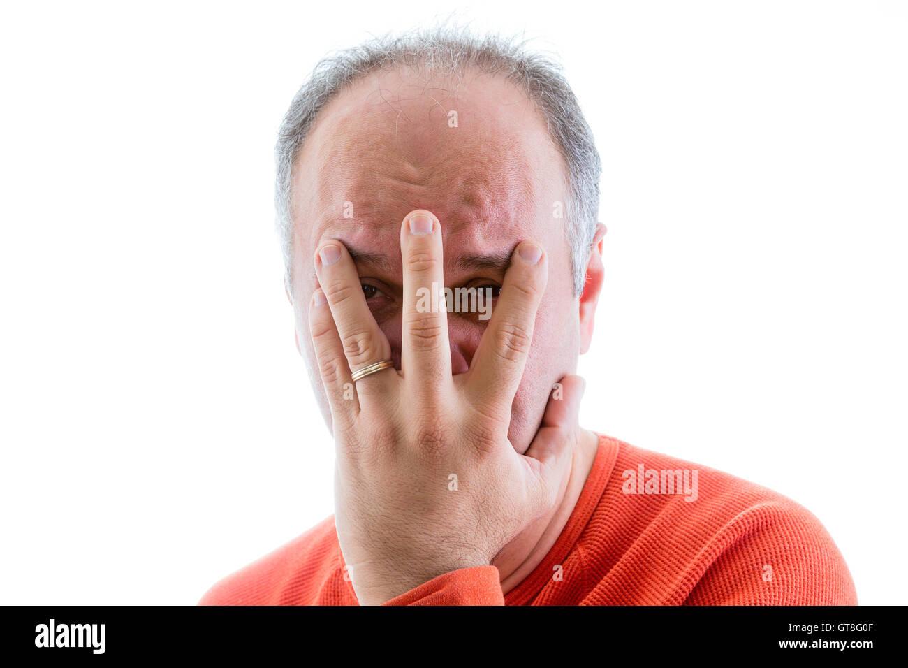 Guilty man filled with remorse hiding his face with his hand peering ...